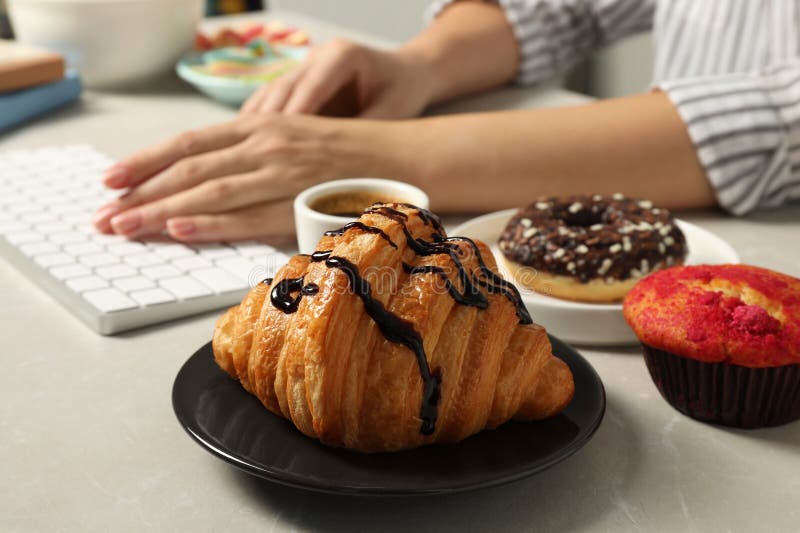 Bad Eating Habits. Woman Working on Computer at Light Grey Marble Table ...