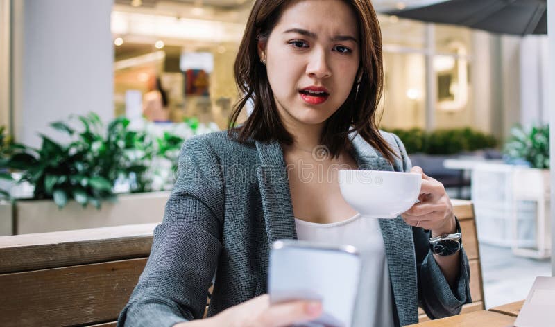 Baffled Young Asian Woman with Coffee Cup and Smartphone Stock Image ...