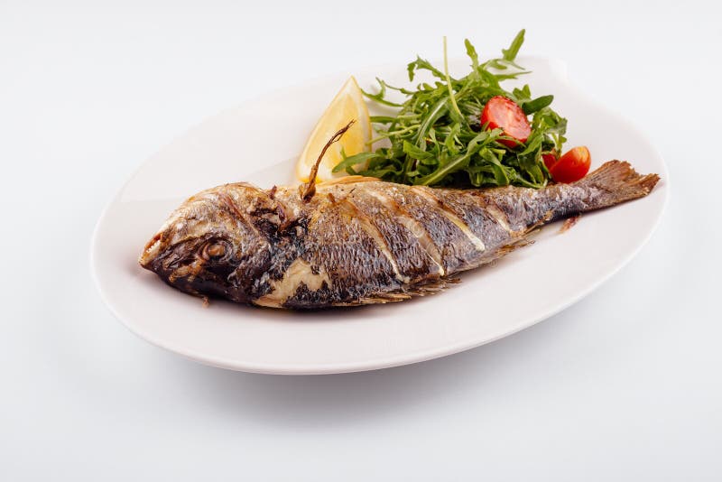 Baked Sea Bream Fish with Arugula Salad and Tomatoes Stock Image ...