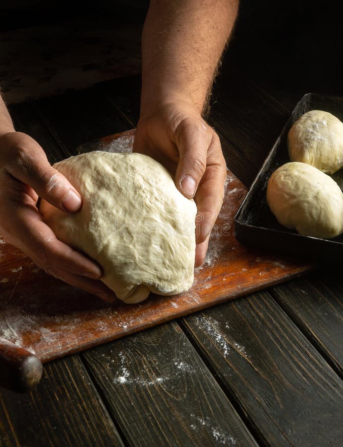 The Baker Hands Knead the Dough for Buns on the Kitchen Table Close-up ...
