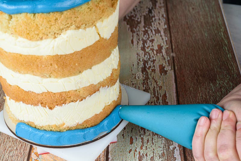 Baker Using a Icing Nozzle To Put Blue Frosting on the Base of the Cake ...