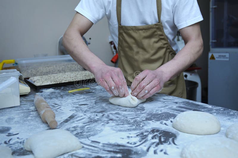 At the Bakery: Baker Standing at the Work Table and Forming Dough for ...