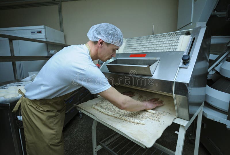 At the Bakery: Baker Working a Dough Forming Machine Forming Dough for ...