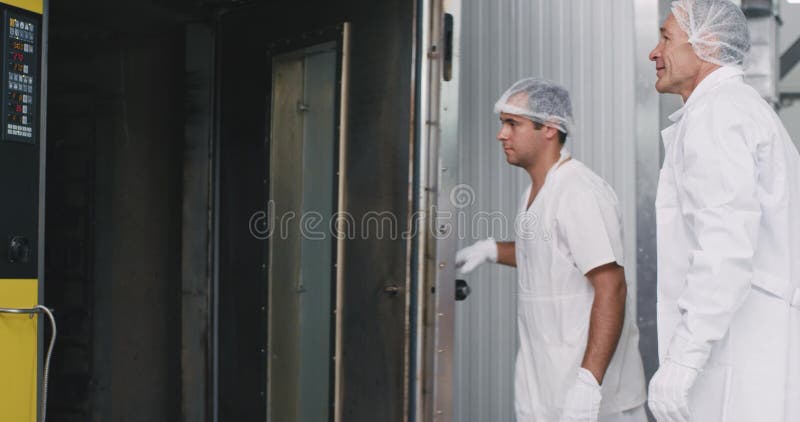 Bakery Engineer and His Assistance in a White Uniform Load the Bread on ...
