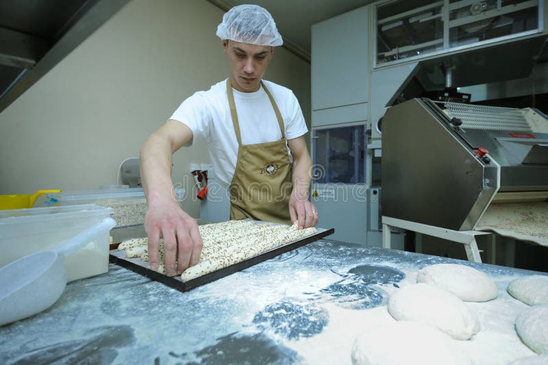 At the Bakery: Man Baker Puts Formed Dough on a Tray Preparing for ...
