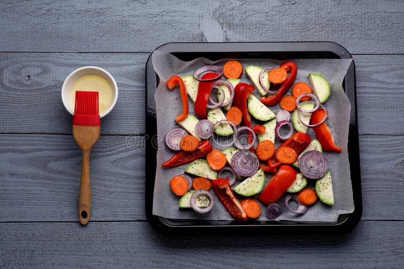 Baking Pan with Parchment Paper and Raw Vegetables on Grey Wooden Table ...