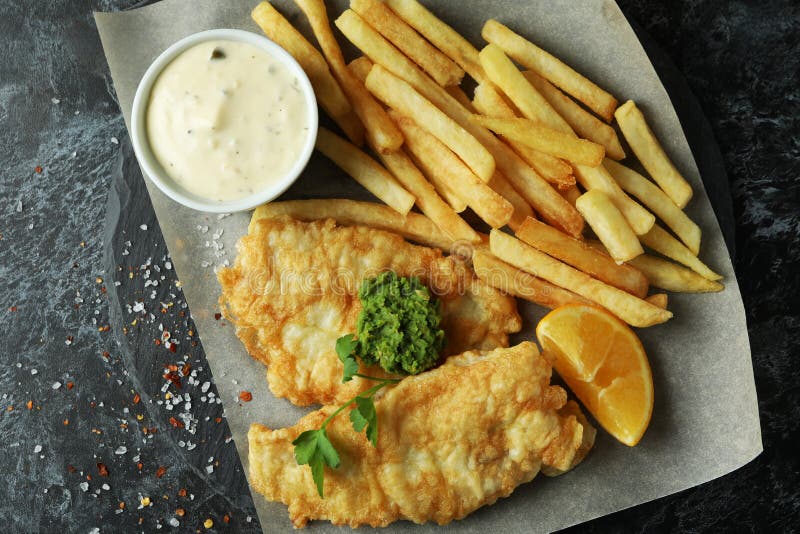 Baking Paper with Fried Fish and Chips on Black Smokey Table Stock ...