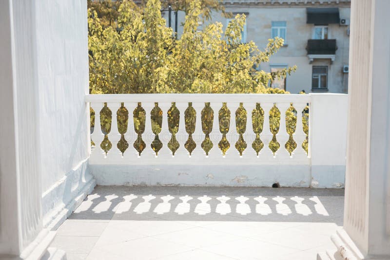 A Balcony with a Railing and a Tree in the Background. the Railing is ...
