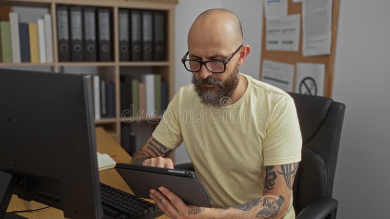 Bald Man with Beard Sitting in an Office Using a Tablet in Front of a ...