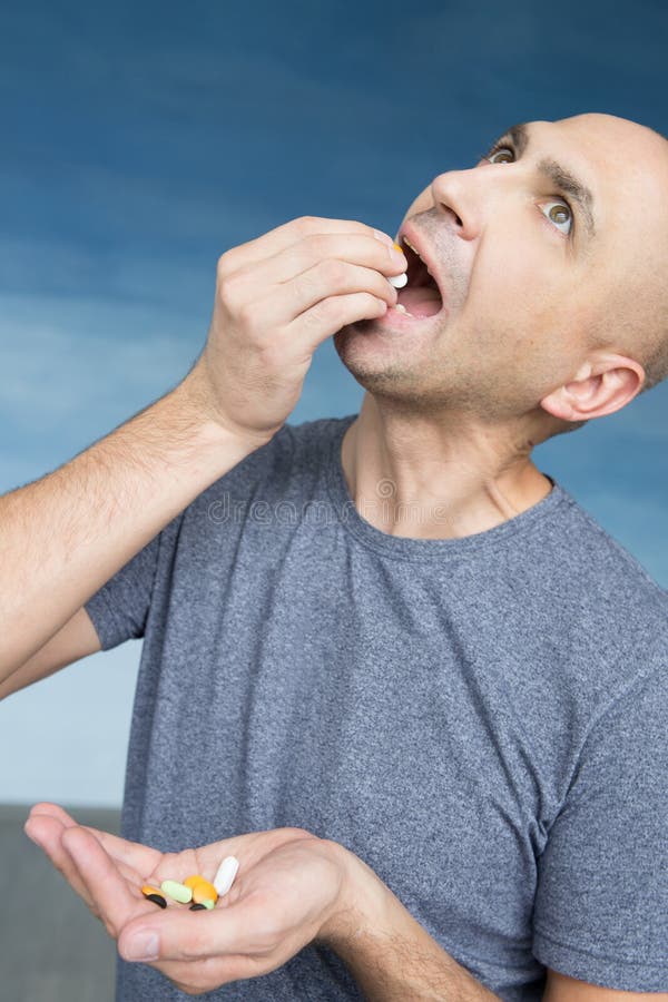 A Bald Man Eats Pills with Greed Stock Photo - Image of indoors ...