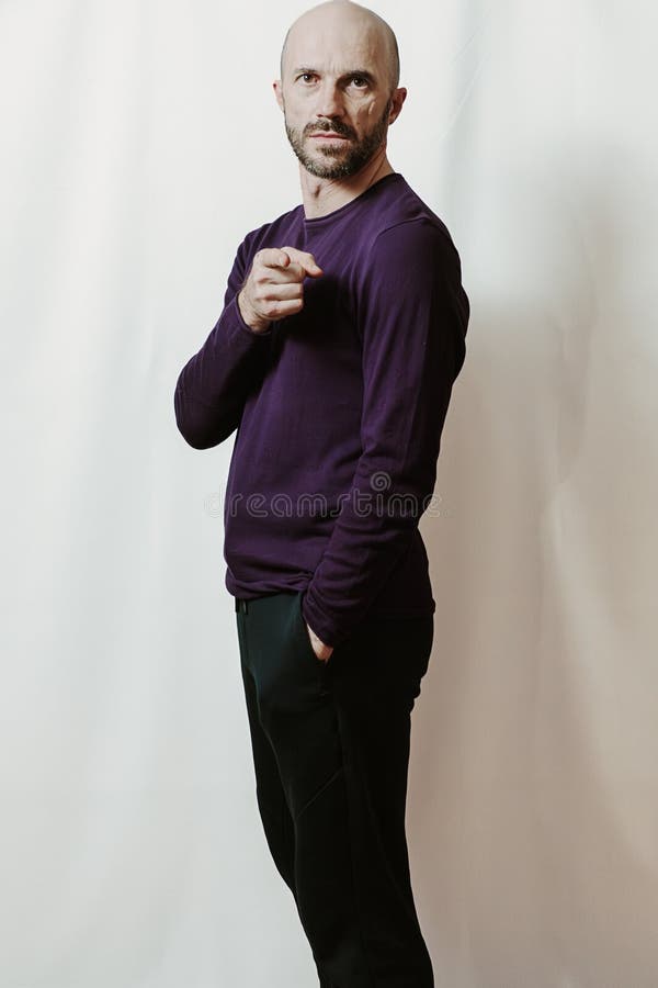 Bald Man in a Lilac Sweater Poses on a White Background. he Points His ...