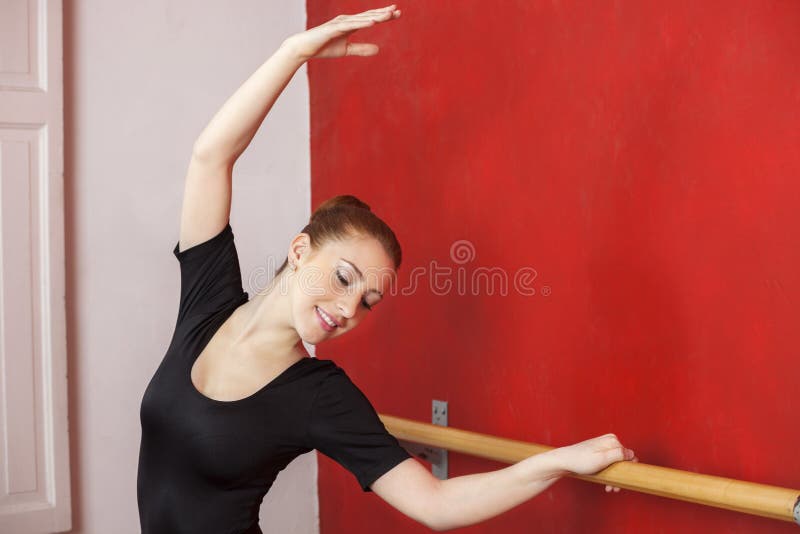 Ballet Dancer Stretching Hand at Barre in Studio Stock Image - Image of ...