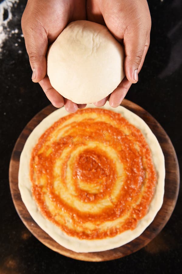 Balls of Fresh Pizza Dough in Hand and Tomato Sauce on Pizza Base Stock ...