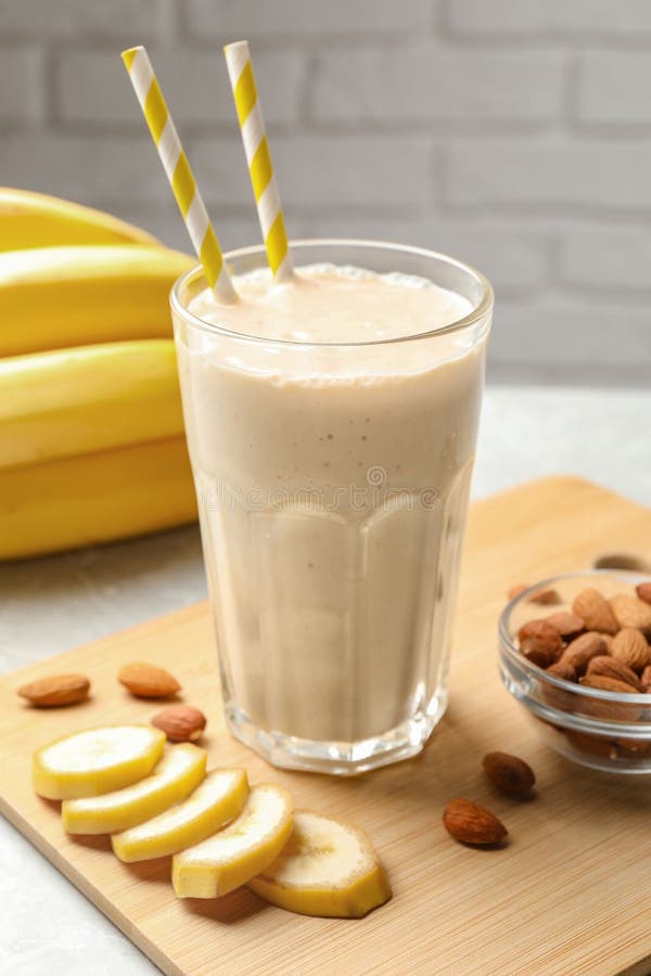 Banana Smoothie in Glass and Nuts on Table Against White Brick Wall ...