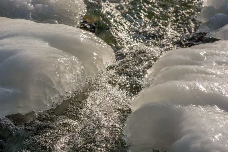 Dew Water Flows Down a Mountain with a Thick Layer of Ice on the Shore ...
