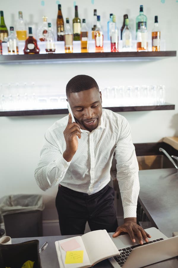 Bar Tender Talking on Mobile Phone at Bar Counter Stock Image - Image ...