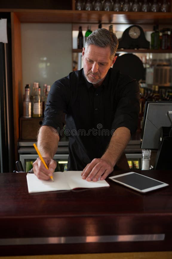 Bar Tender Writing in a Book Stock Image - Image of business ...