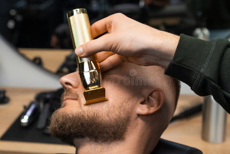Young Barber Carefully Cuts the Mans Hair with a Trimmer in the ...