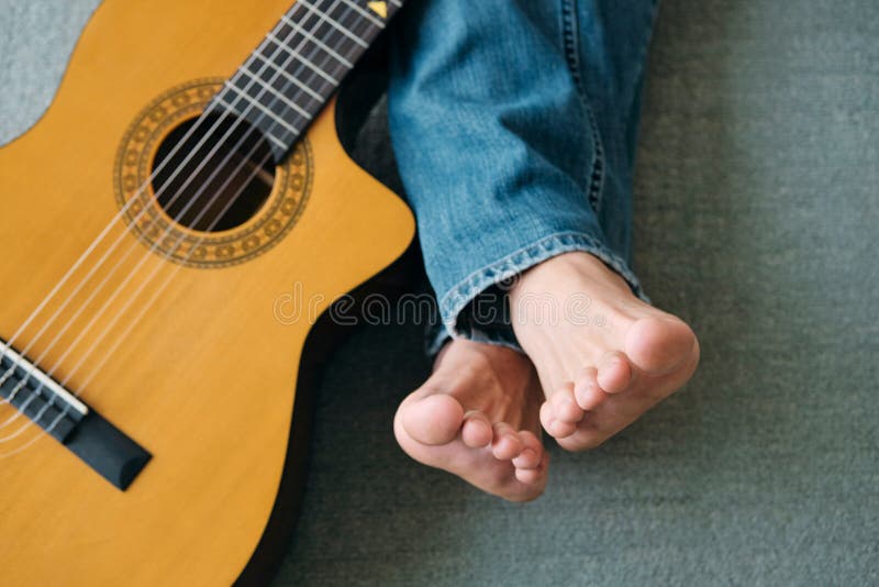 Barefoot Guitarist with Legs Outstretch beside Guitar Stock Photo ...