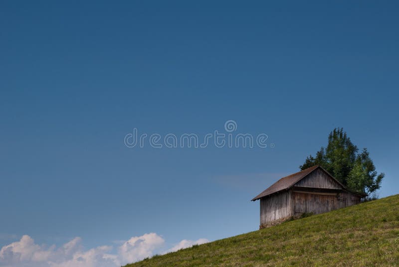Barn on a Slope with Tree and Blue Cloudy Sky Behind Stock Image ...