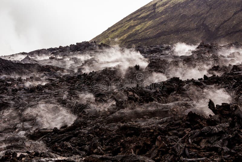 Barren Lava Fields Steaming in Light Rain with Green Volcano Slope in ...