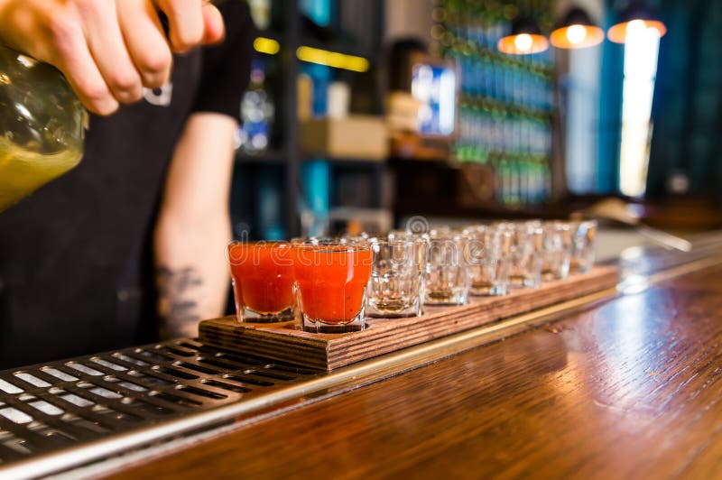 The Bartender at the Bar Pours Red Tincture into Shots Stock Photo ...