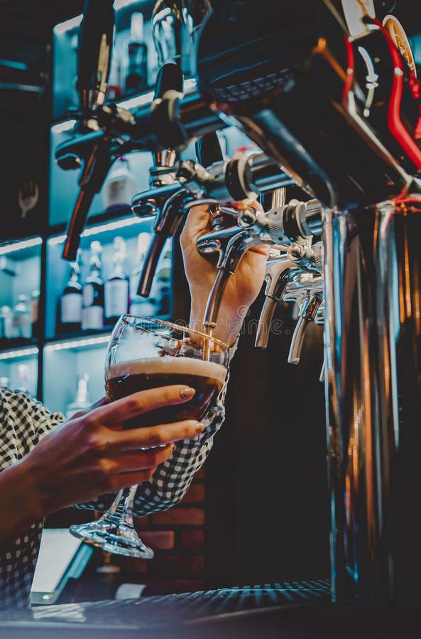 Bartender Hand at Beer Tap Pouring a Draught Beer in Glass Serving in a ...