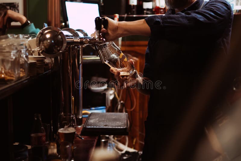 Bartender Pours Dark Beer from Tap in Pub Behind the Bar Stock Image ...