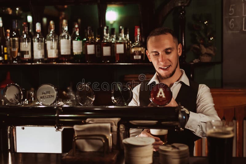 Bartender Pours Draft Beer into a Glass from the Tap Behind the Bar ...