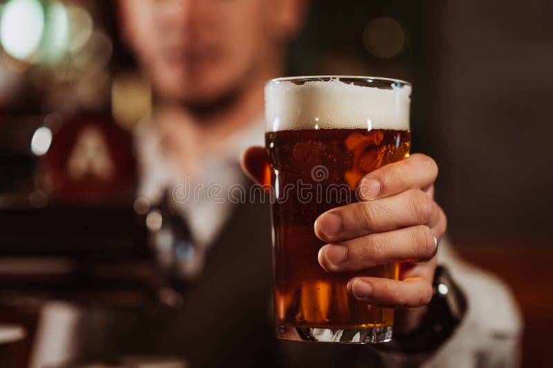 Bartender& X27;s Hand with a Glass of Light Draft Beer with Foam in Bar ...