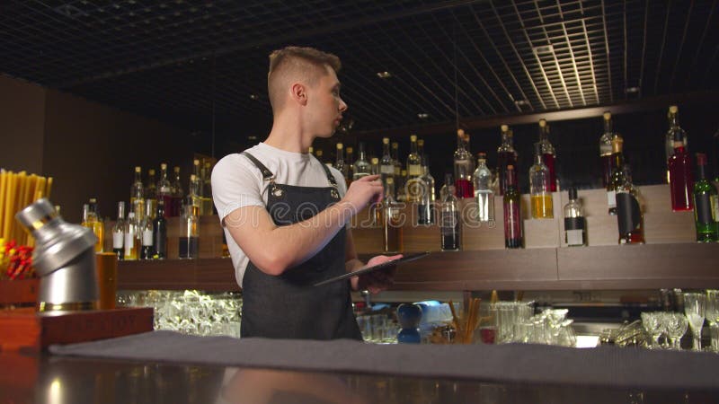 Bartender Stands with Tablet and Counts Bottles with Alcohol Stock ...