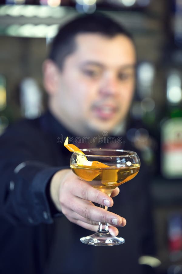 A Young Guy Working As a Bartender Behind a Bar is Preparing Drinks ...