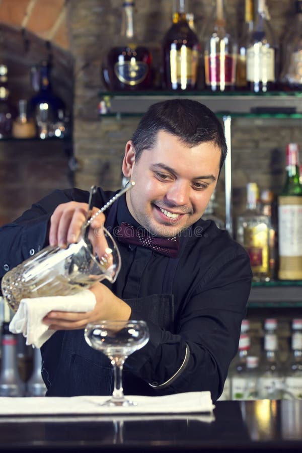 A Young Guy Working As a Bartender Behind a Bar is Preparing Drinks ...