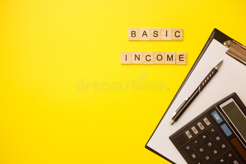 Basic Income Written on Wood Blocks Calculator on Yellow Background ... Basic Income Written on Wood Blocks Calculator on Yellow Background ...