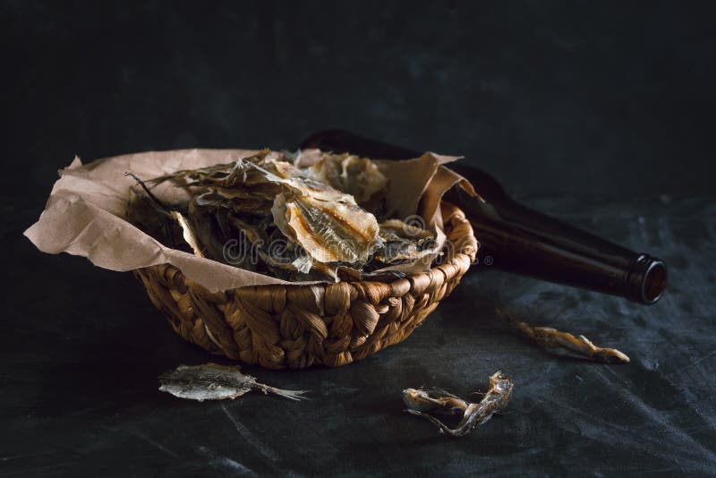 Basket of Dried Fish in Craft Paper and an Empty Bottle on a Dark ...