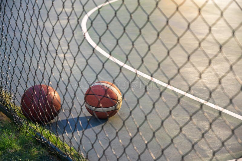 Basketball Ball on Illuminated Playground at Night with Metal Net on ...