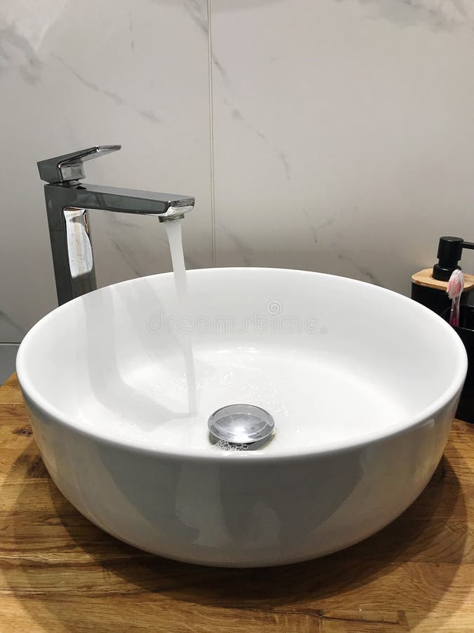 In the Bathroom, Water Runs from the Tap into the Round Wash Basin ...
