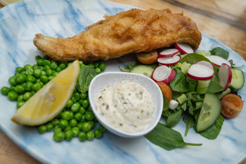 Batter on a Cod Fish on a Plate. in Shallow Focus is a Salad and Peas ...