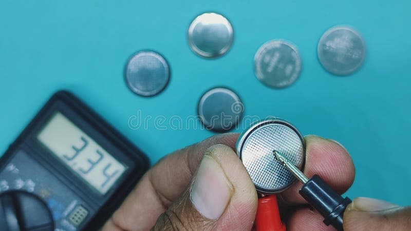 Battery Button Cells, Fingers and Multimeter with Green Background ...