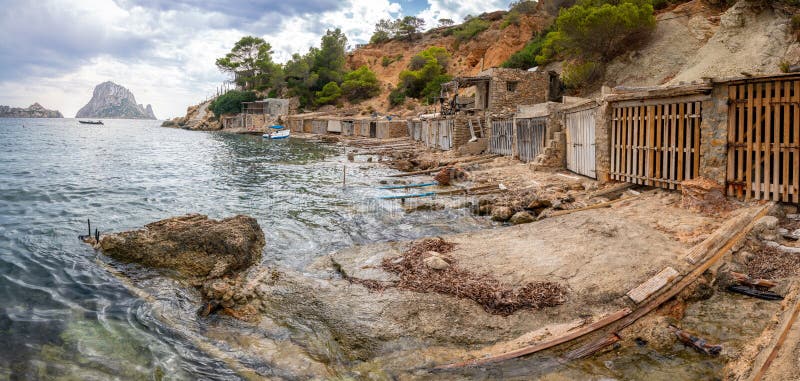 Beach in Es Vedra with Boat Garages and a Cloudy Sky in the Background ...