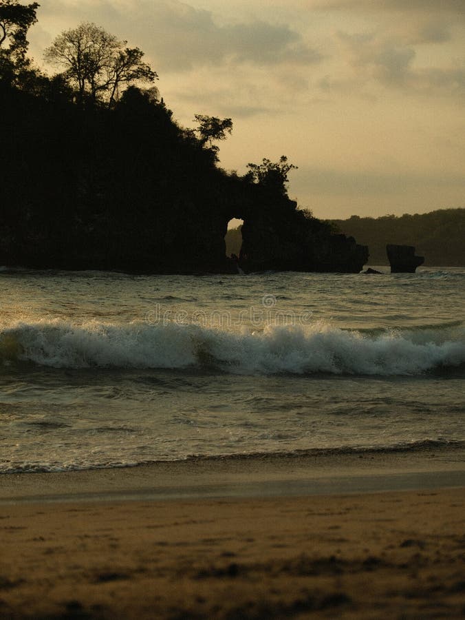 A Beach with a Large Rock in the Middle of it Stock Image - Image of ...