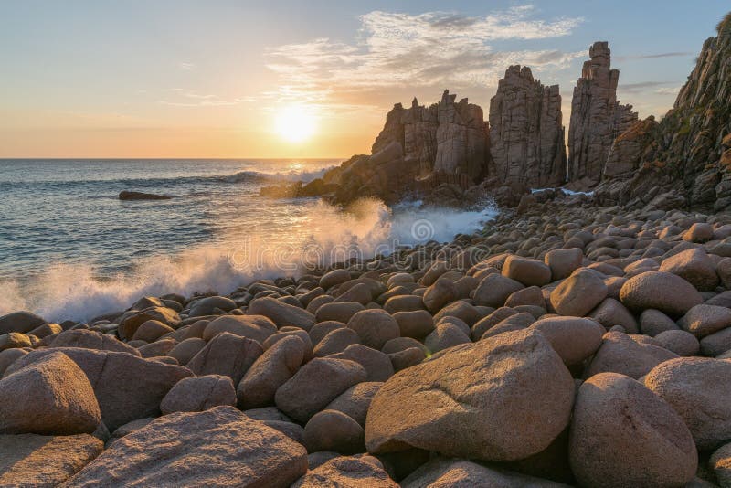 Beach Shore with Large Rocks and Crashing Waves Illuminated by the Warm ...