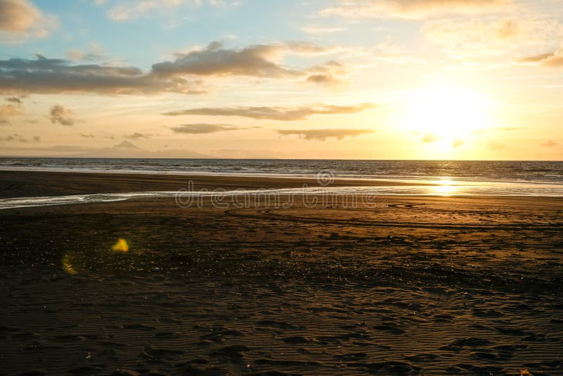 Beach in Silhouette As Sunsets on Distant Horizon Over Ocean Stock ...
