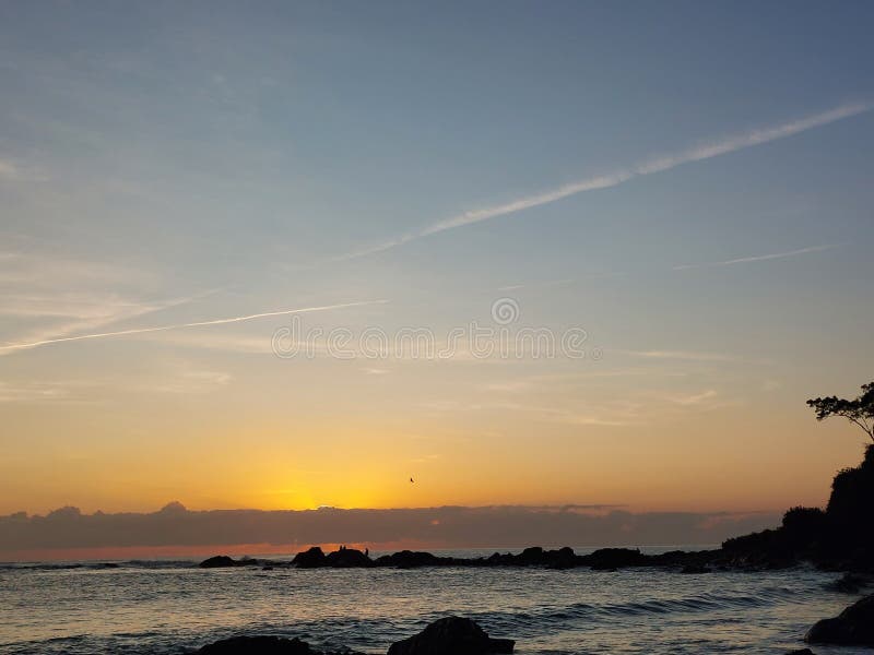 On a Beach Surrounded by Rocks, the Sun Rises between Clouds Coloring ...