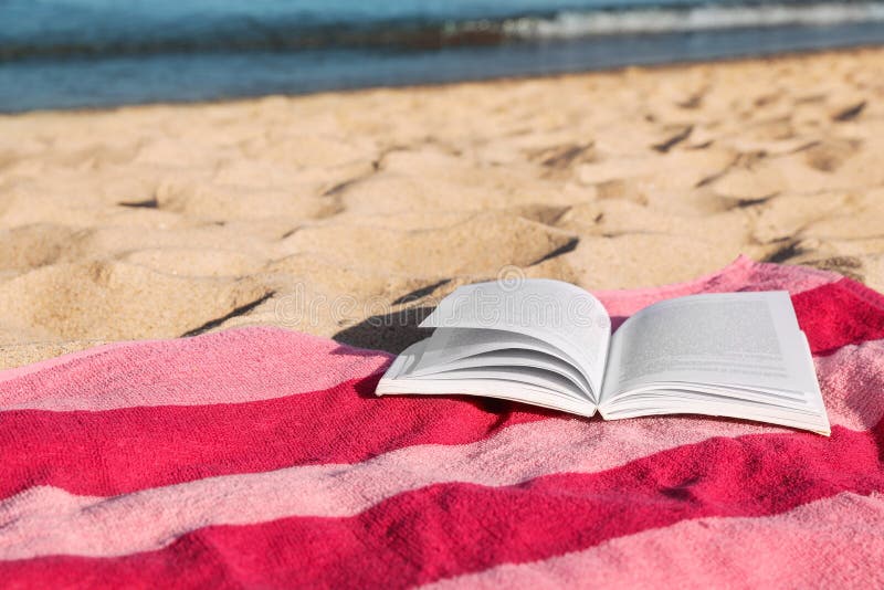 Beach Towel and Open Book on Sand Near Sea, Space for Text Stock Image ...