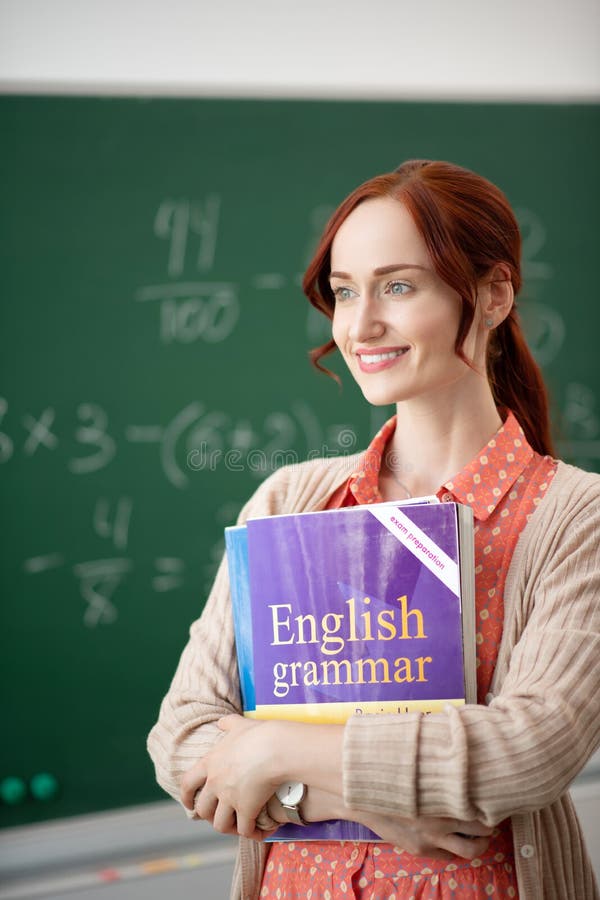 Beaming Teacher Holding Books Standing in Classroom Stock Photo - Image ...