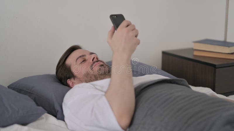 Young Man Using Smartphone while Laying in Bed Stock Image - Image of ...