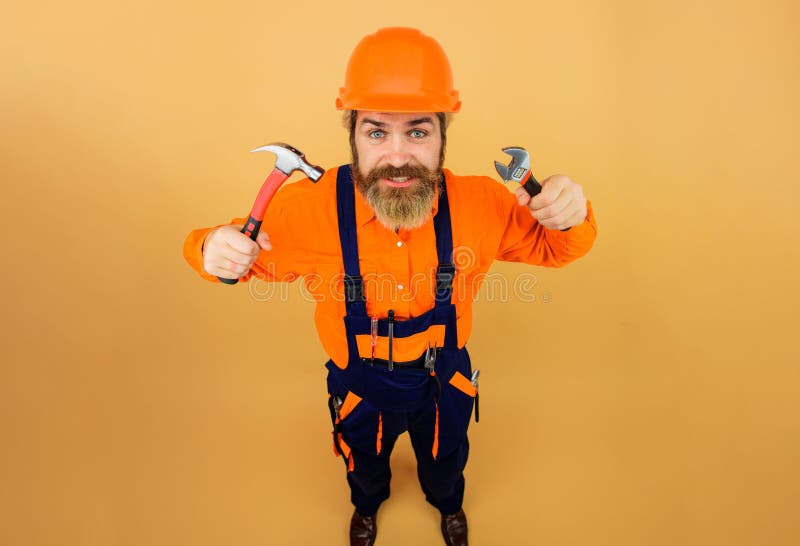 Bearded Builder in Safety Helmet and Overalls with Hammer and ...