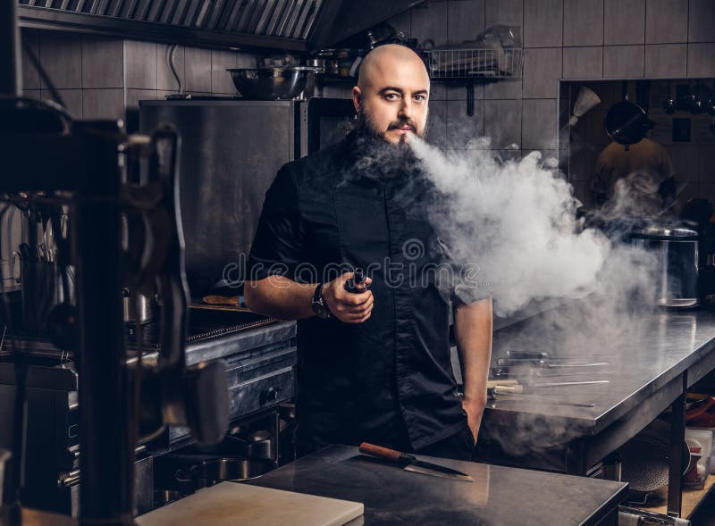 Bearded Chef in Black Uniform Smoking E-cigarette while Standing in the ...