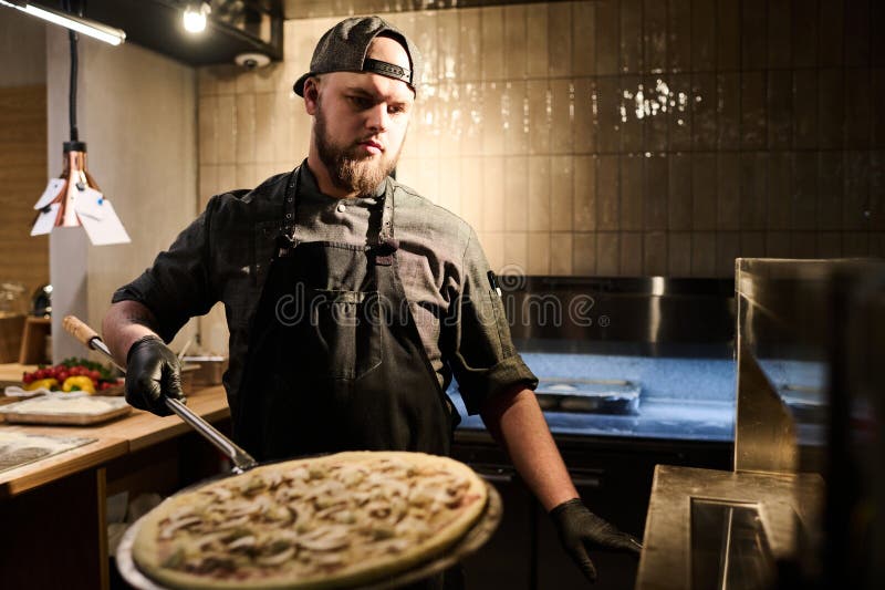 Bearded Chef in Grey Uniform and Cap Standing in Front of Electric Oven ...
